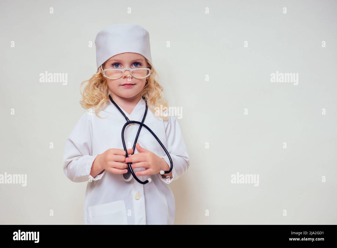 Adorable child girl uniformed as doctor wearing doctor's cap and ...