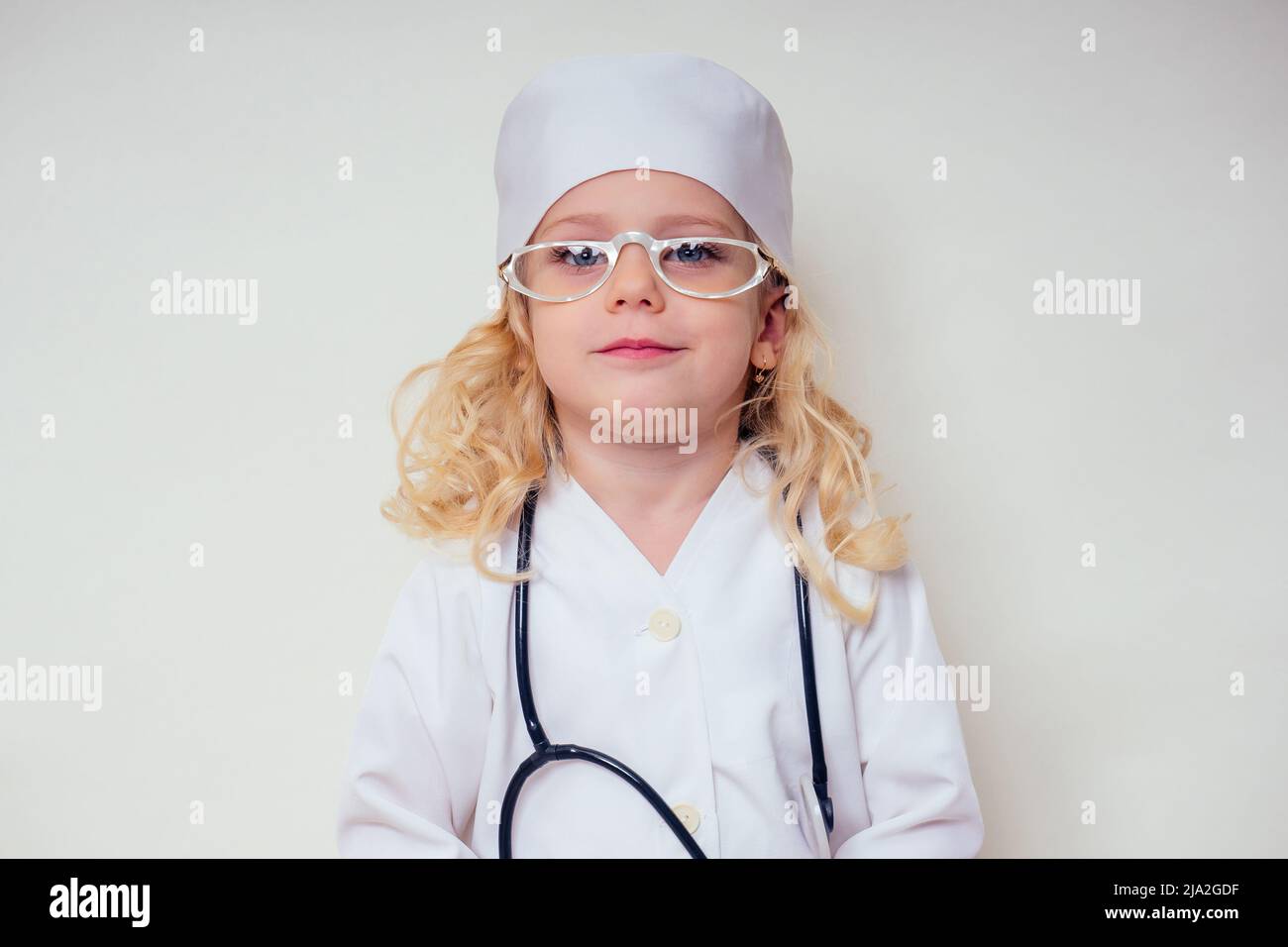 Adorable child girl uniformed as doctor wearing doctor's cap and ...