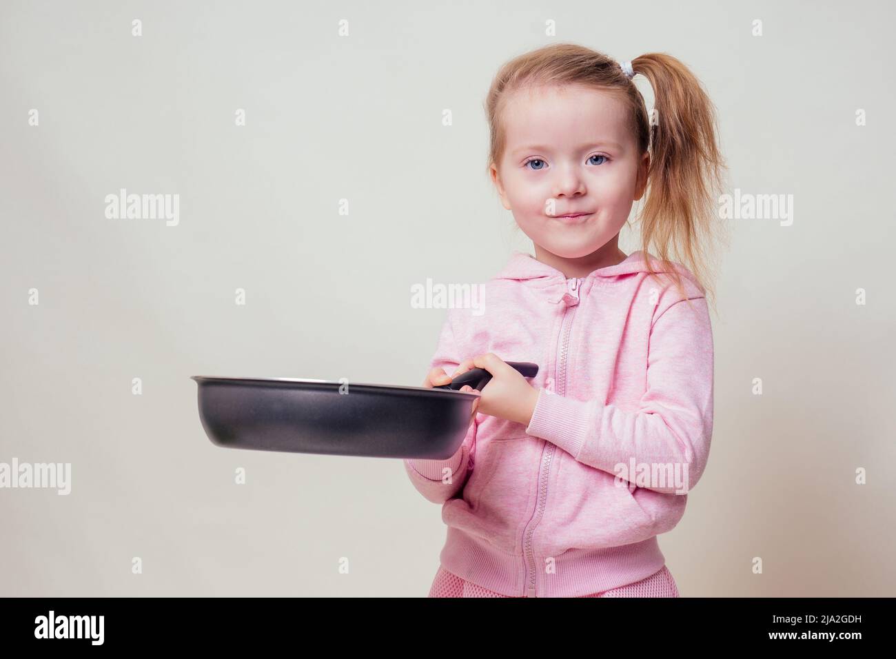 Little girl female chef holding a frying pan preparing national dish on ...