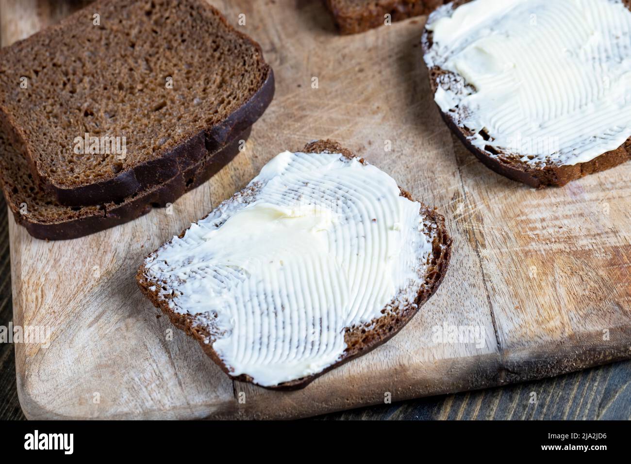 spread butter on black rye bread, slices of black sliced bread with ...