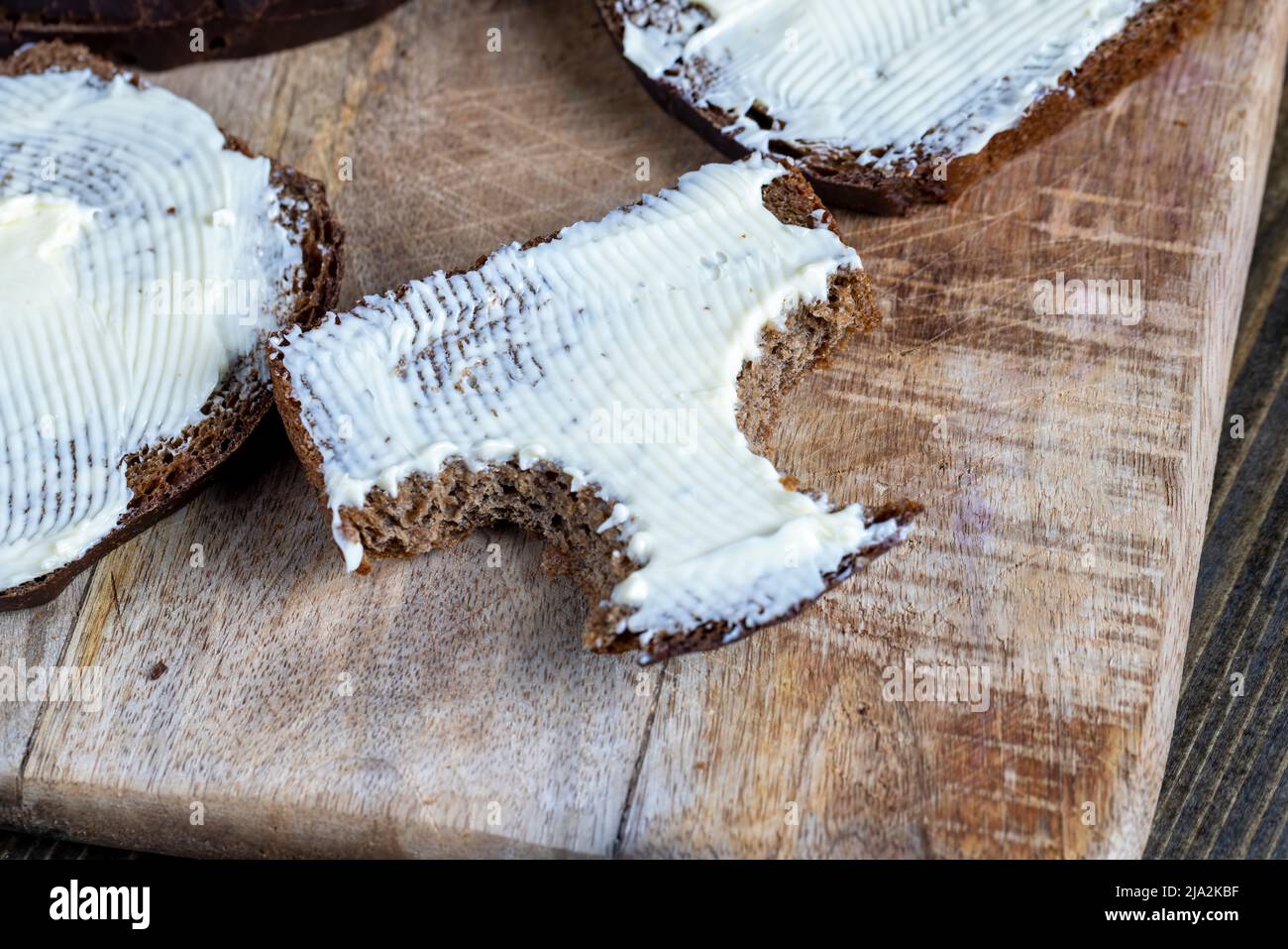 spread butter on black rye bread, slices of black sliced bread with ...