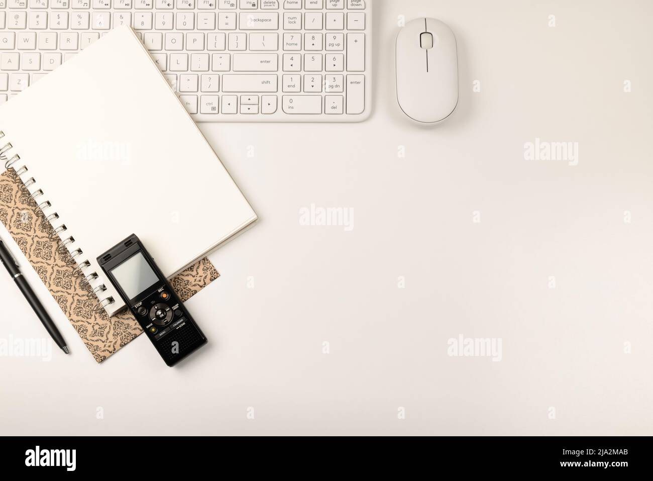 White keyboard, mouse and notepad with black pen and voice recorder ...
