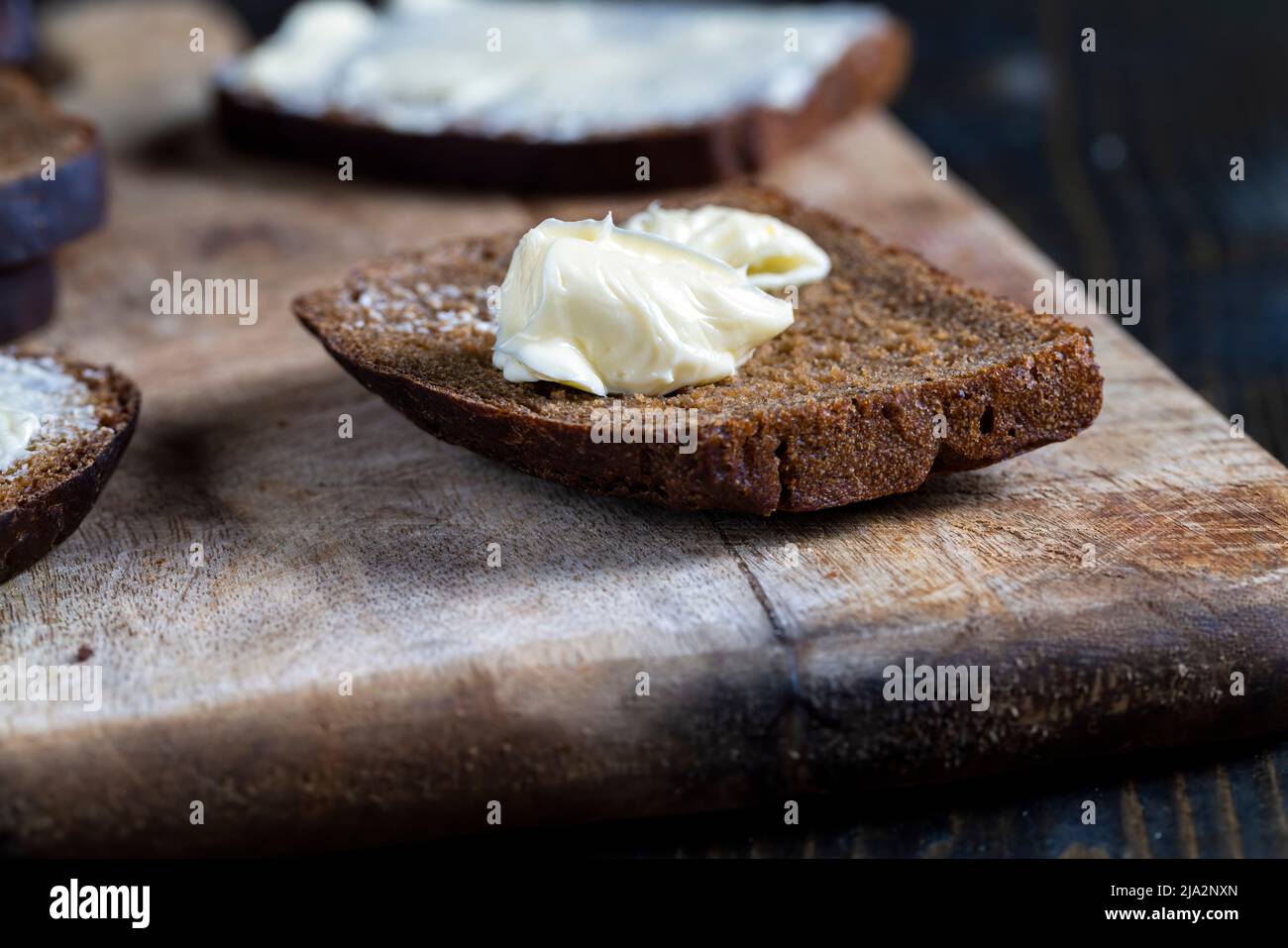 spread butter on black rye bread, slices of black sliced bread with ...