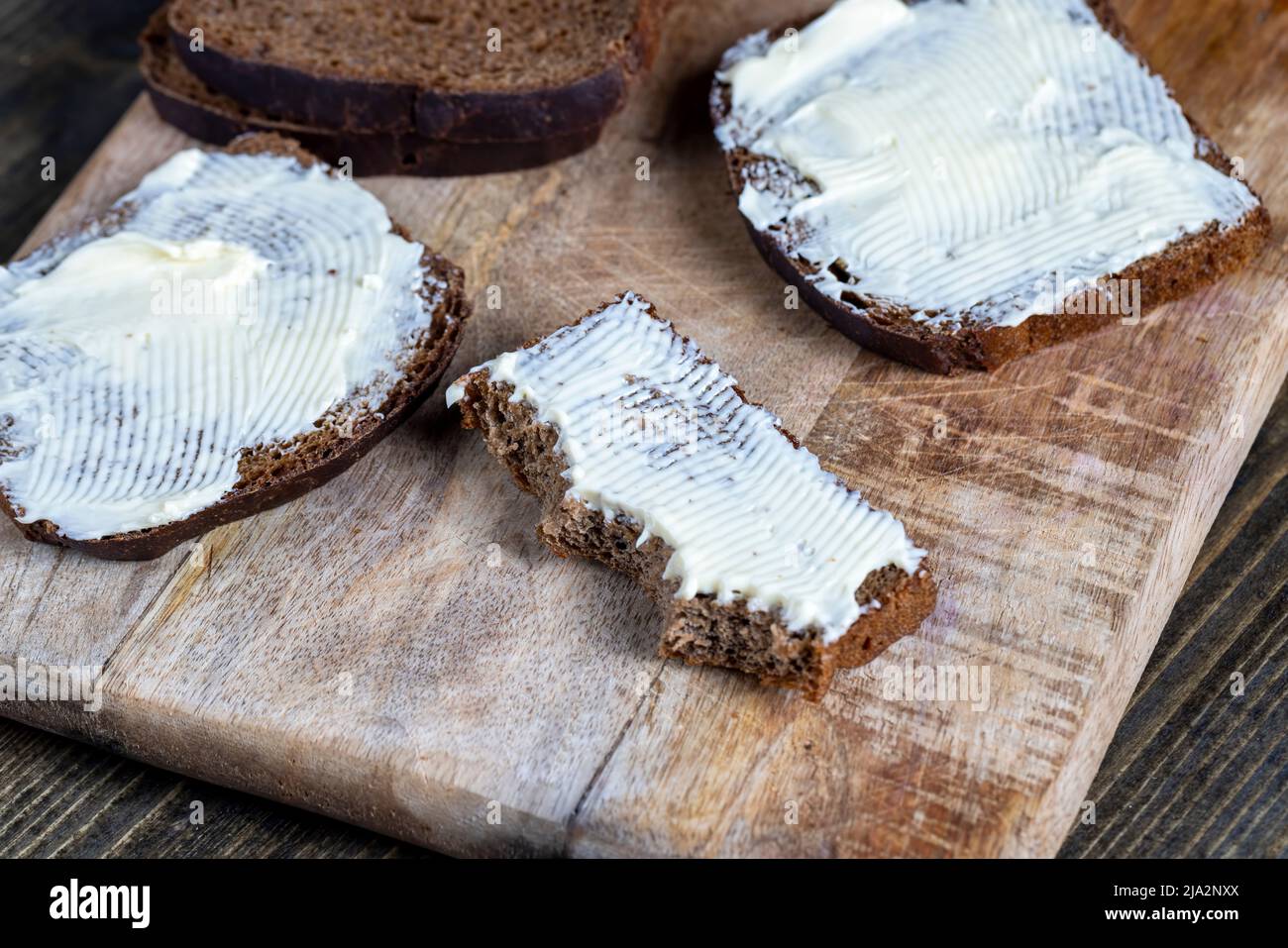 spread butter on black rye bread, slices of black sliced bread with ...