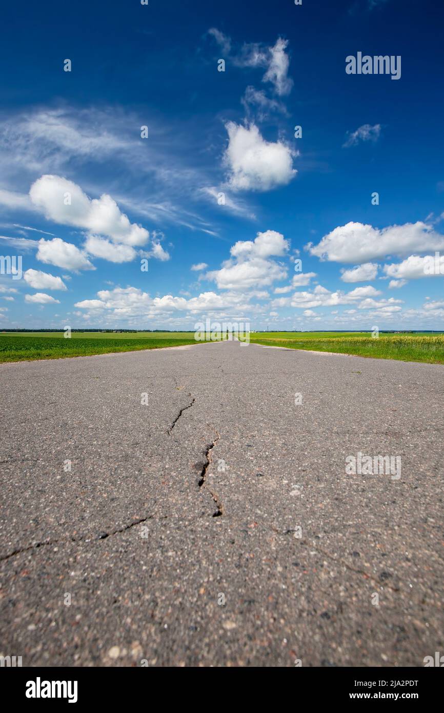 paved highway with blue sky and clouds, a highway through a field with ...