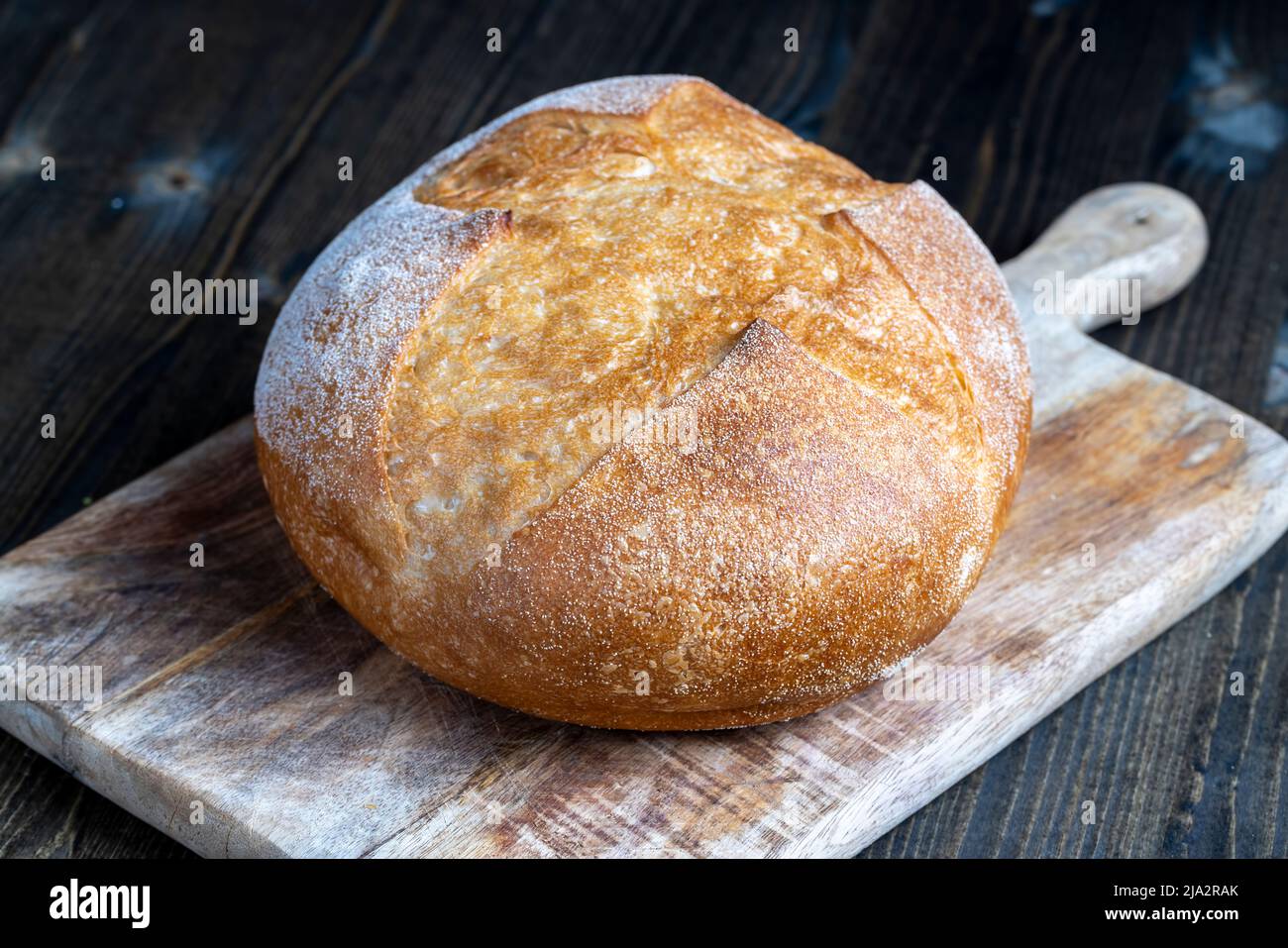 a whole loaf of bread on a cutting wooden board, a rye loaf of bread on ...