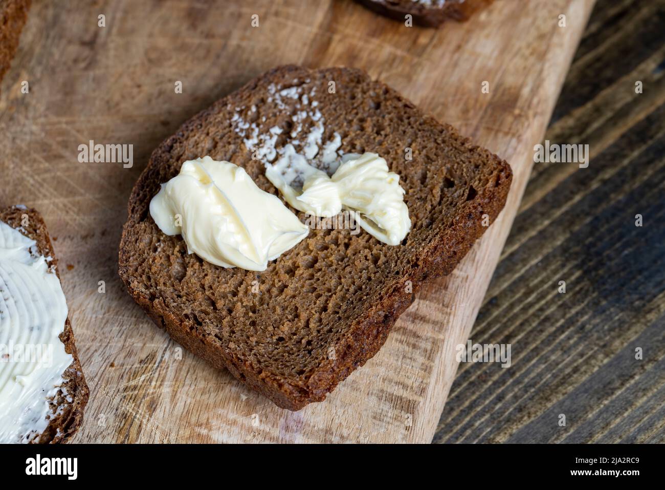 spread butter on black rye bread, slices of black sliced bread with ...