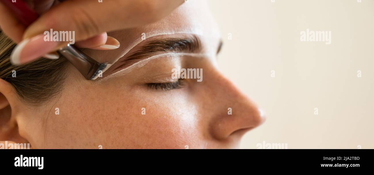 The master draws the shape of the eyebrows with white paint before ...