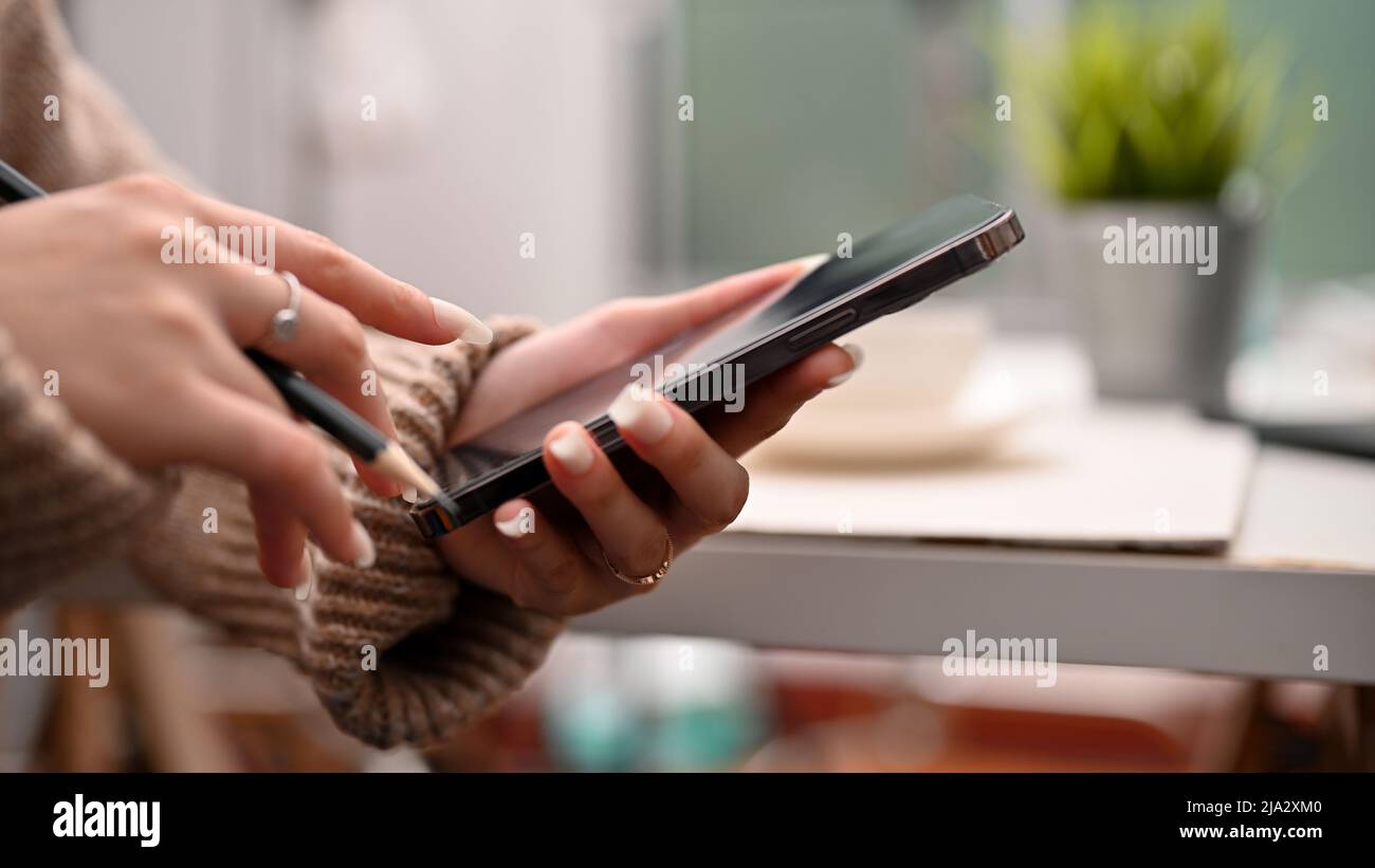 Close-up rear view, A female using smart mobile phone in her office ...