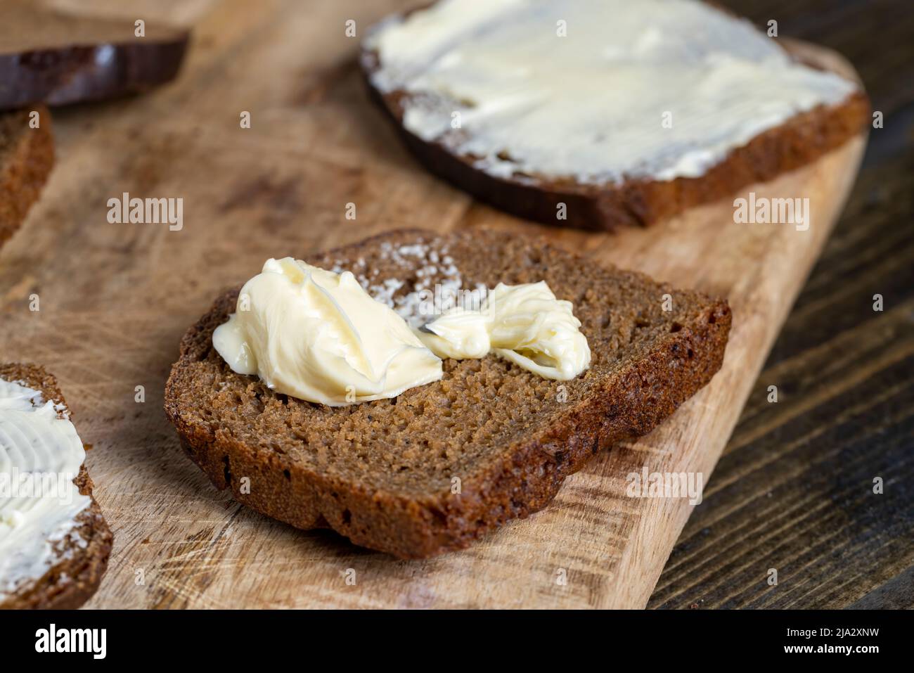 spread butter on black rye bread, slices of black sliced bread with ...