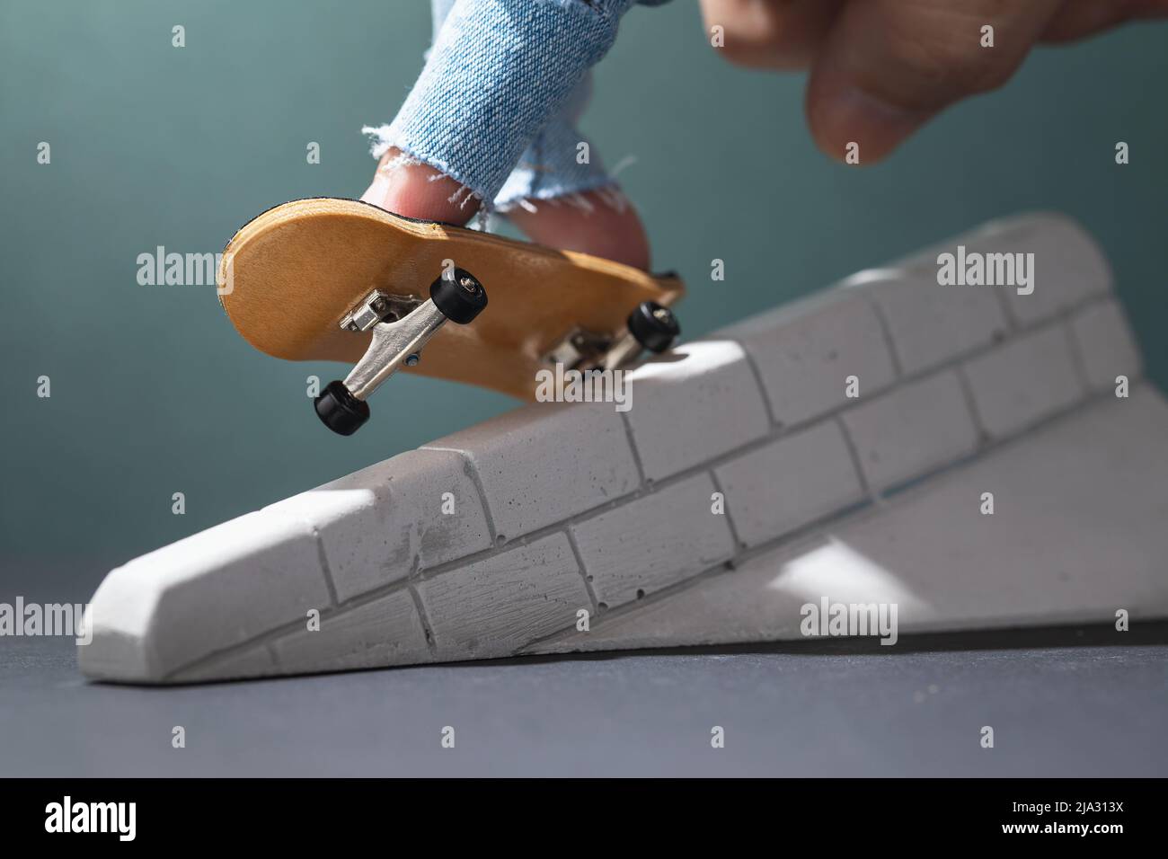 A man rides a small fingerboard on a plaster ramp Stock Photo - Alamy