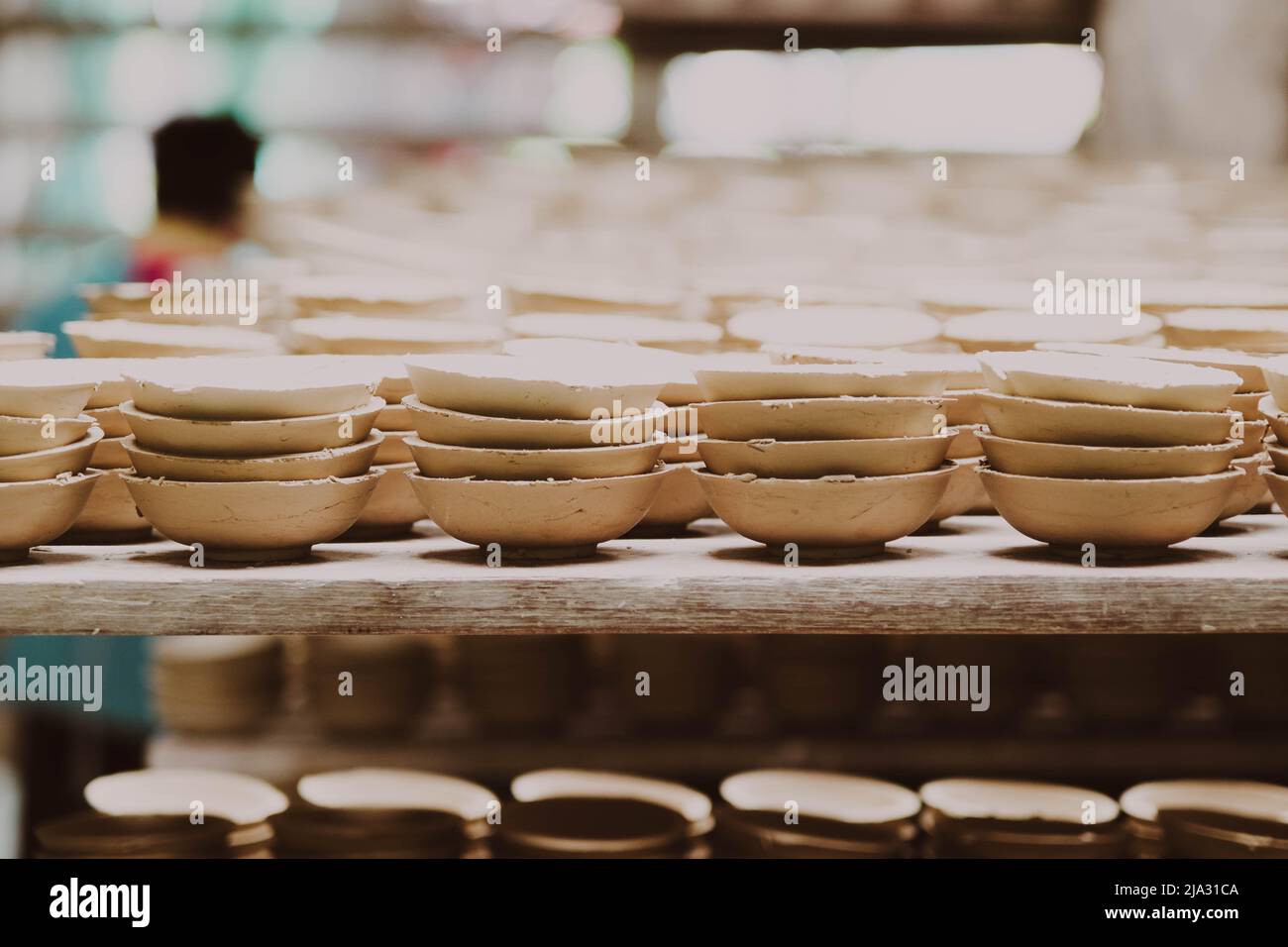Many small round plates made of ceramic clay. Ceramic cup in rack ...