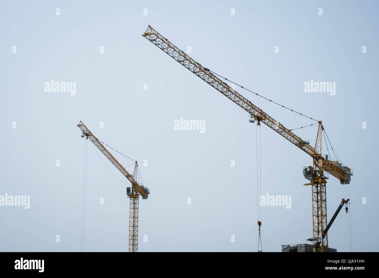 Tower cranes working on a construction site lifts a load at high-rise ...