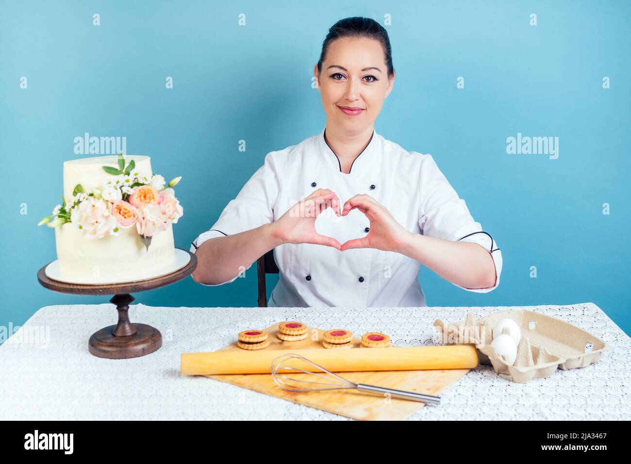 confectioner pastry chef woman shows fingers heart symbol next to ...