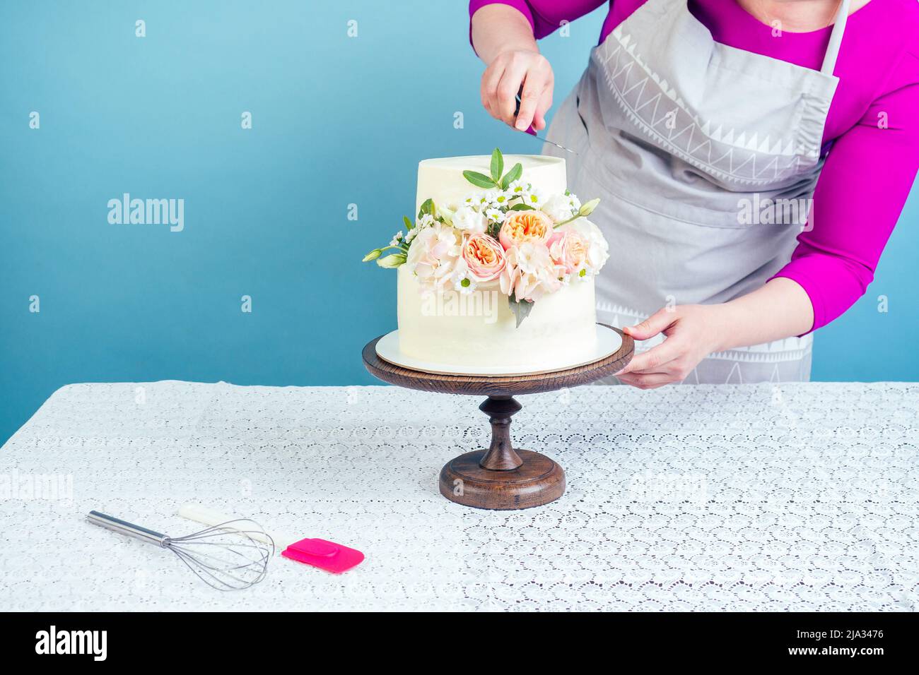 woman confectioner (pastry-cook) decorate appetizing creamy white two ...