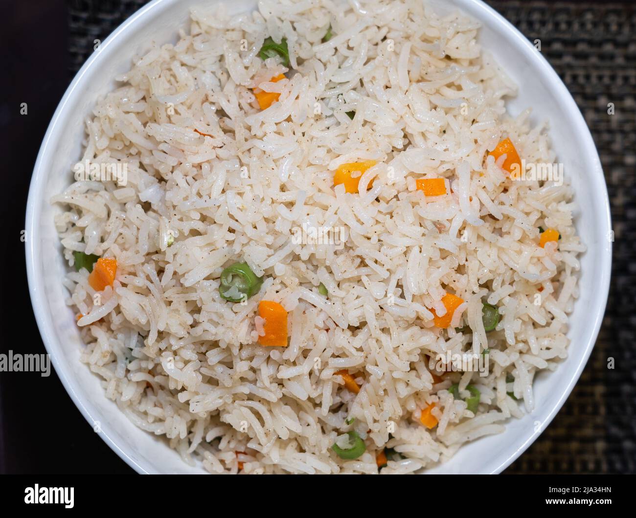 Top view of Vegetable Fried Rice in a white ceramic bowl on table mat ...