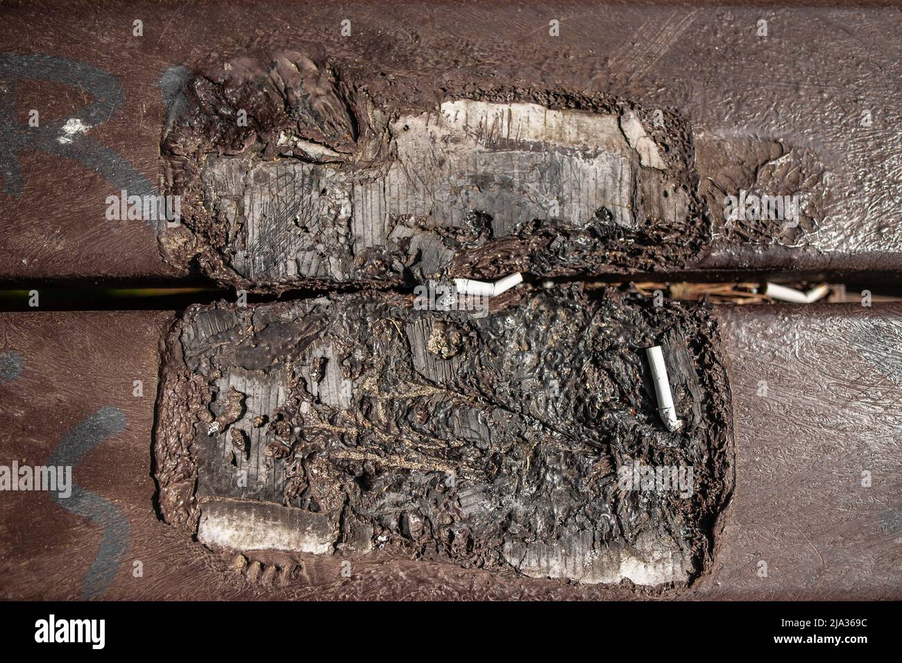 Close up of damaged surface of faux wood table with cigarette butts ...