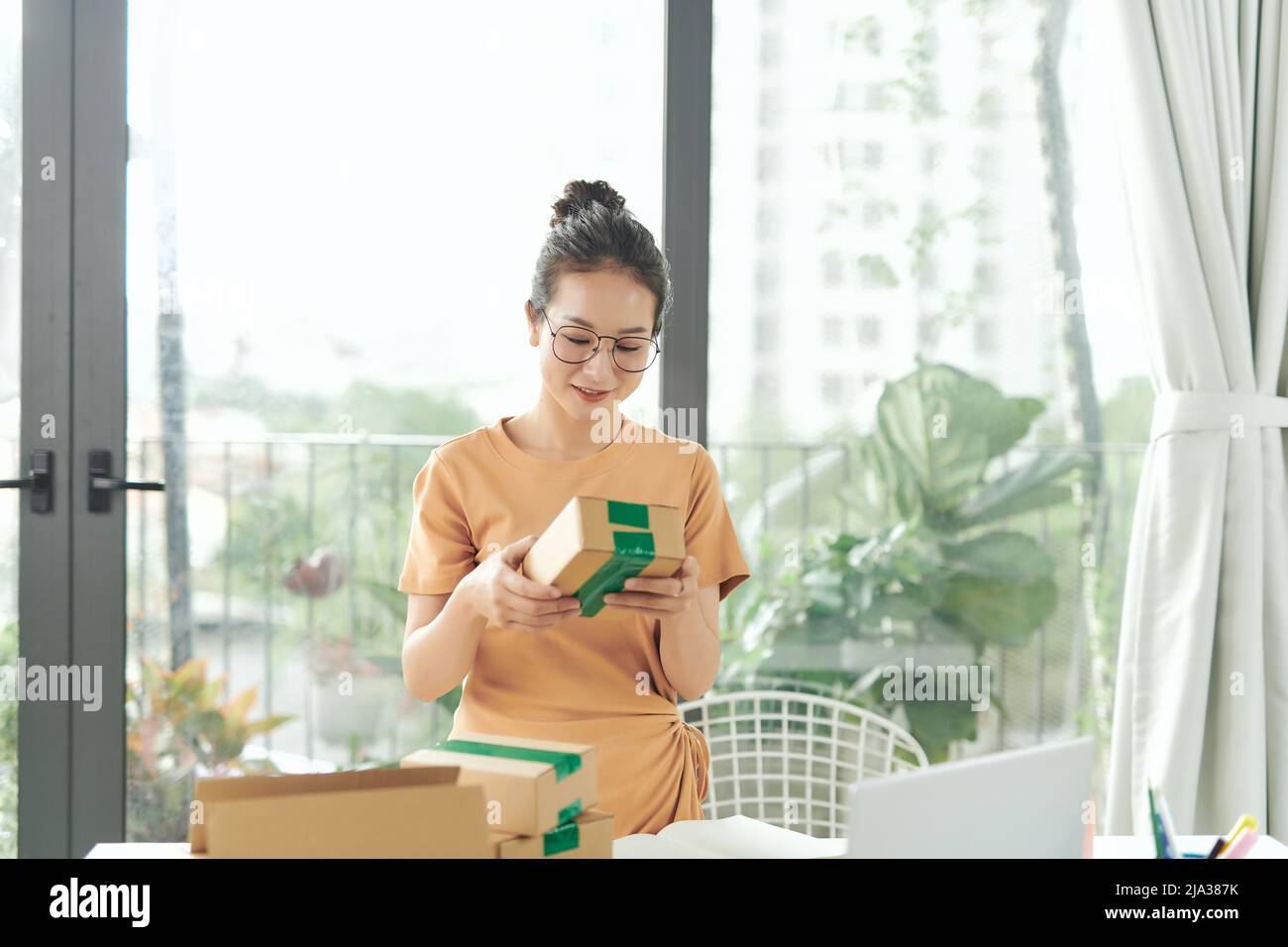 E-commerce businessman is working on a laptop and preparing it for delivery in the office Stock ...