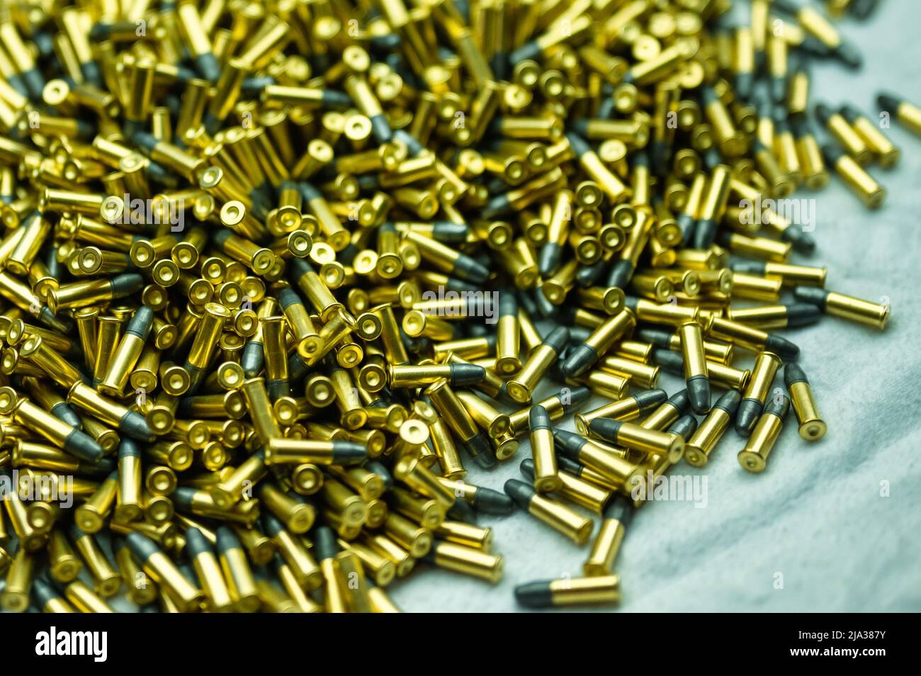 Heap of black and golden small-caliber bullets on table Stock Photo - Alamy