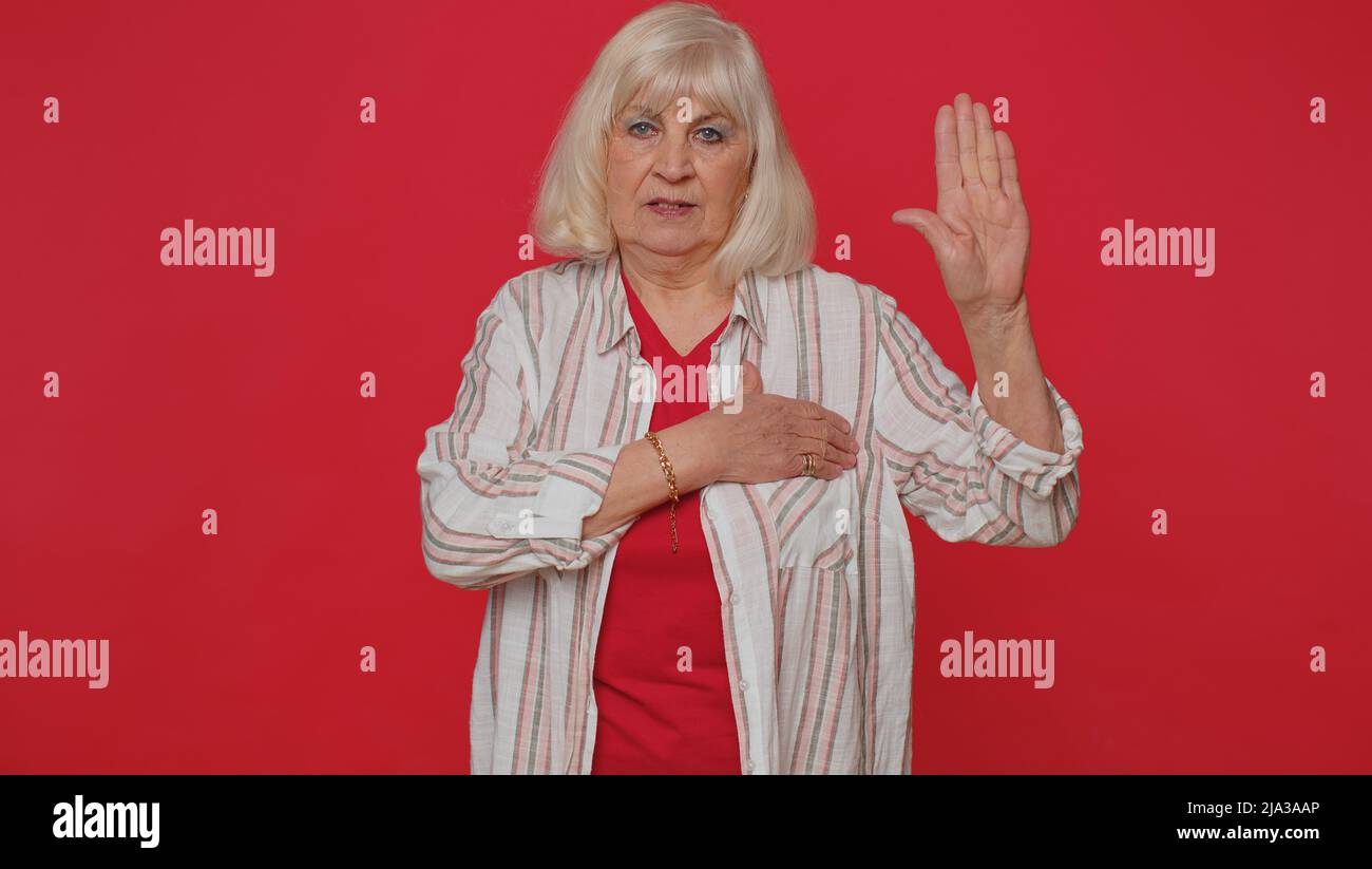 Senior woman raising hand to take oath, promising to be honest, to tell ...