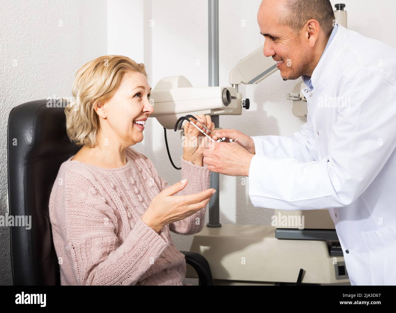 Mature optician examinating eyesight with aid of slit lamp Stock Photo ...