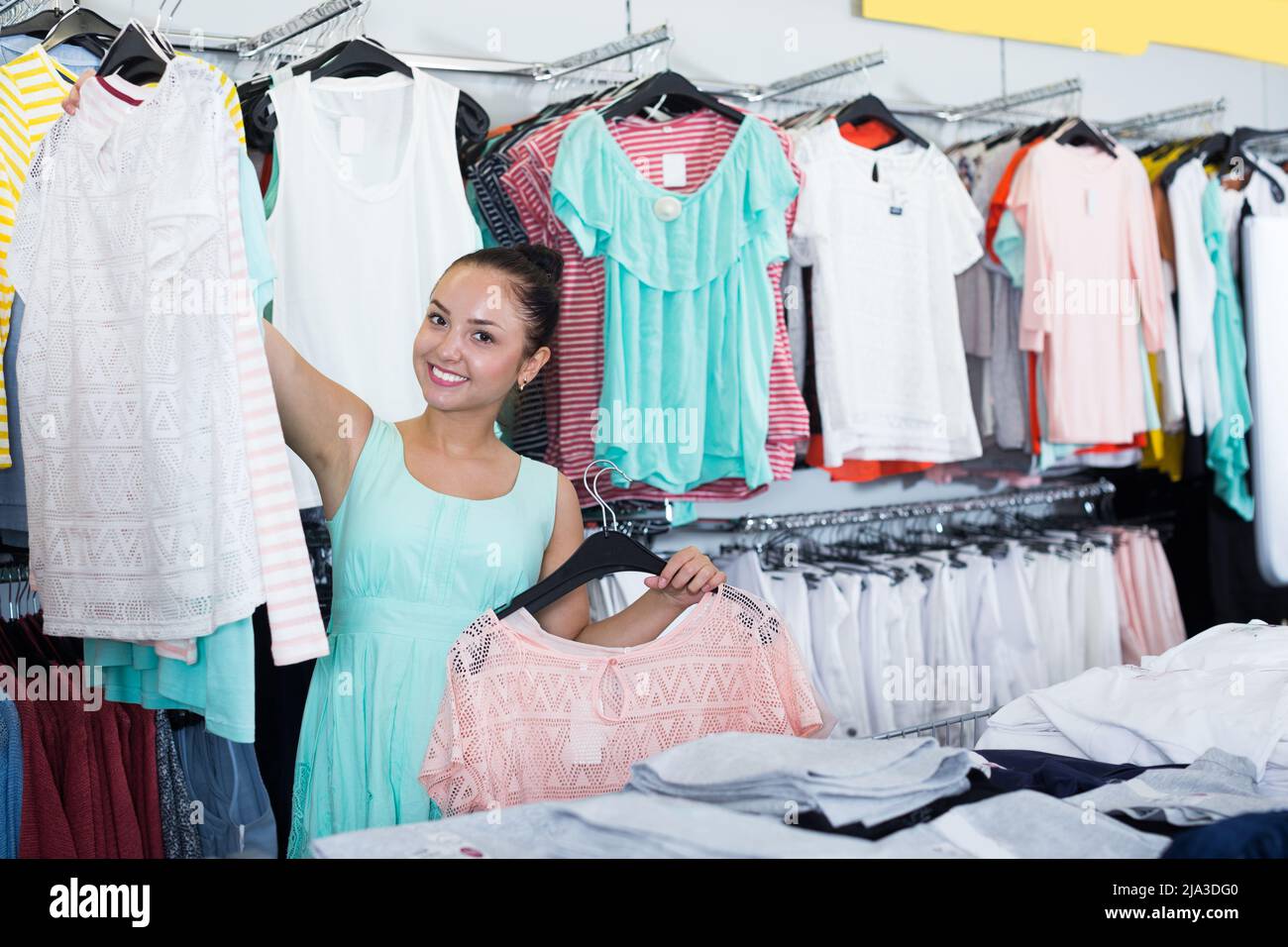 Smiling young woman shopper choosing new garments Stock Photo - Alamy