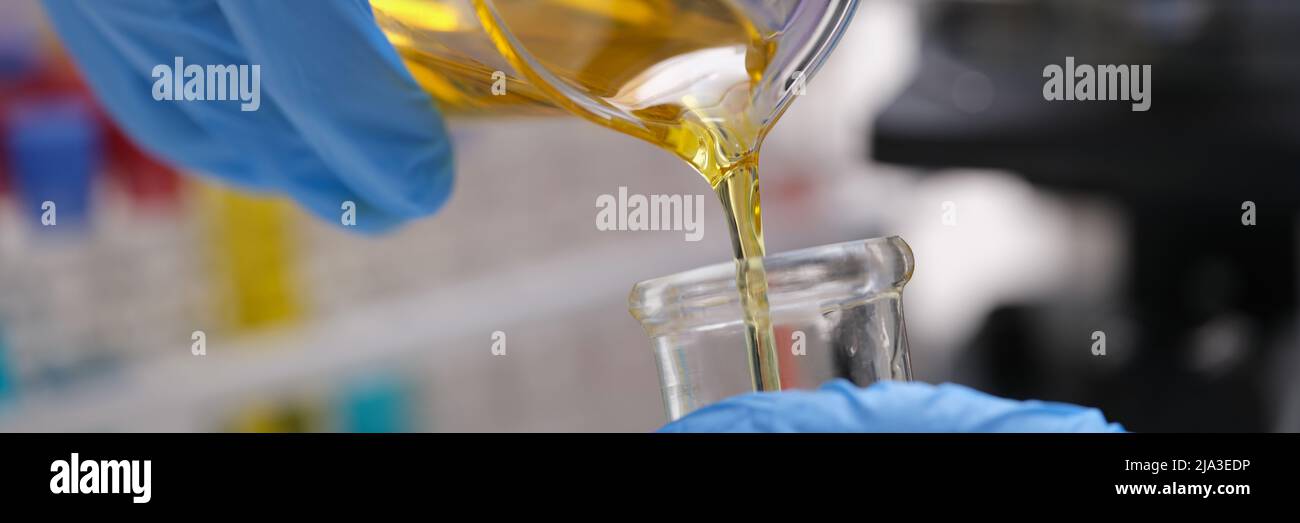 Yellow liquid is pouring into a measuring vessel Stock Photo - Alamy
