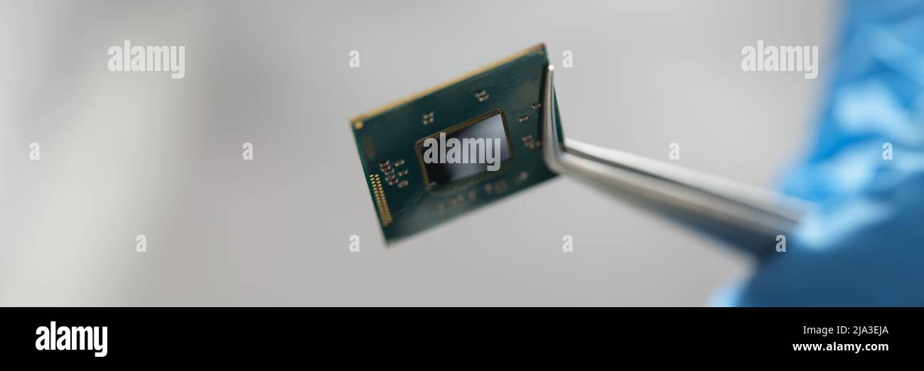 Gloved hands hold a microchip with tweezers, close-up Stock Photo - Alamy