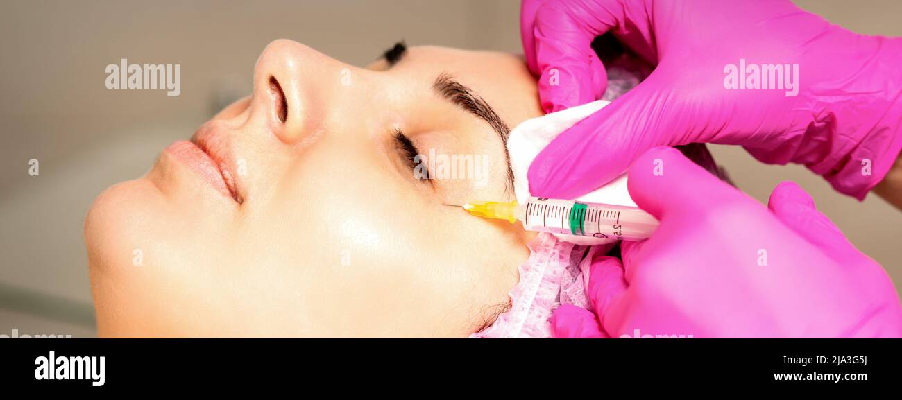 The young white woman is getting rejuvenating facial injections with ...