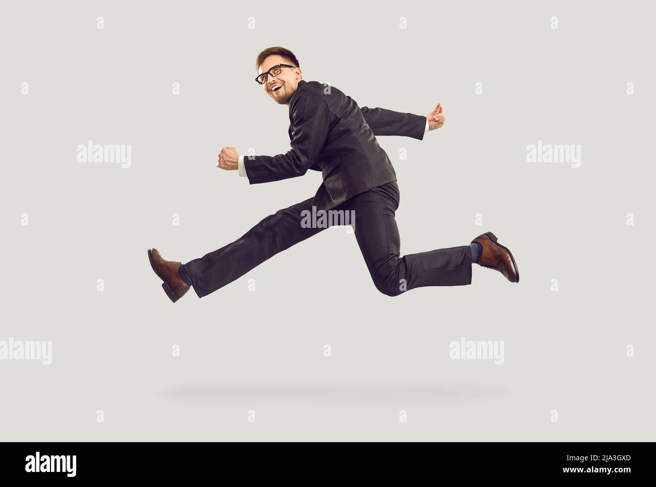 Crazy excited young businessman in black suit running and jumping ...