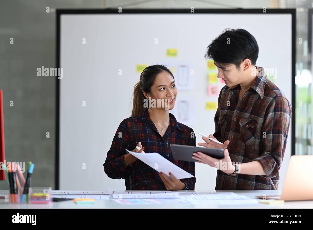 Two young web developers are working together for mobile application software design project ...