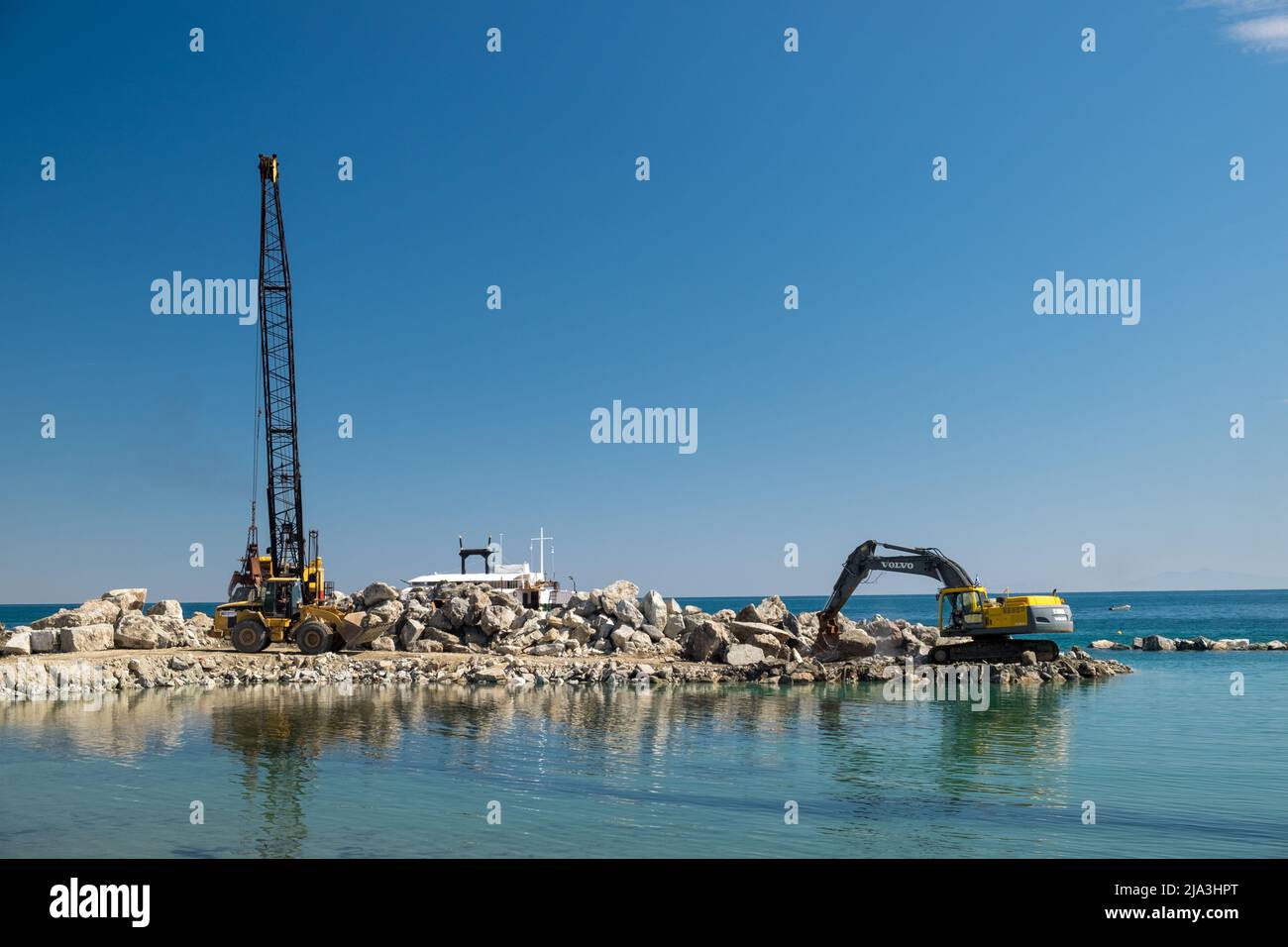 A hydraulic rock handling grab crane and an excavator moving and ...