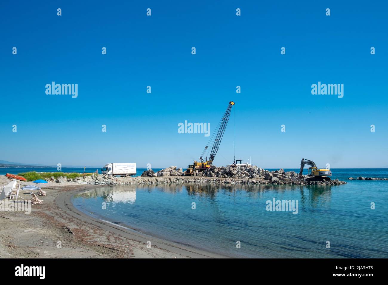 A hydraulic rock handling grab crane and an excavator moving and ...