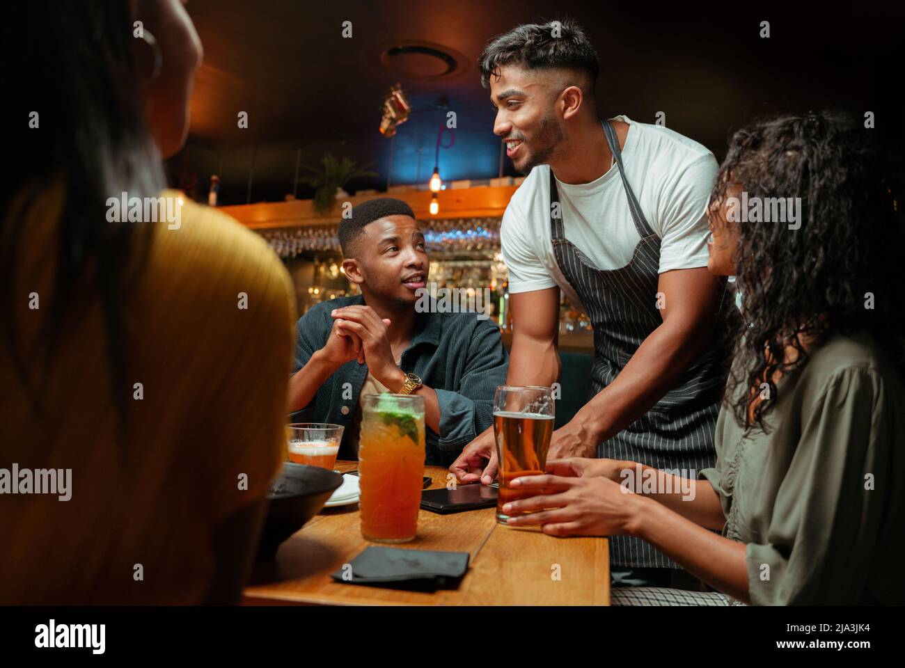Diverse group of friends out for dinner being served by waiter Stock ...