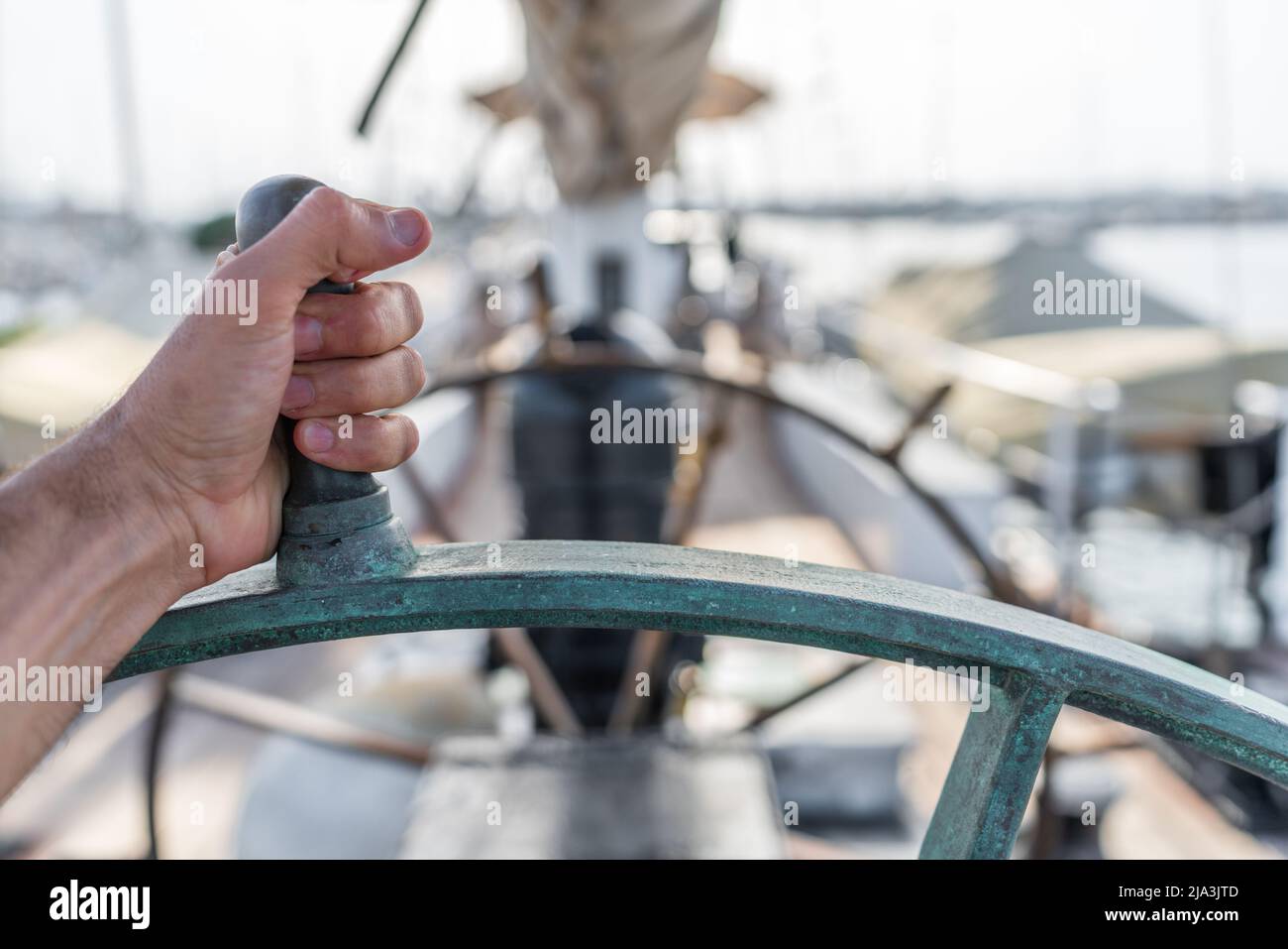 Left hand holding ship wheel with blurred background Stock Photo - Alamy