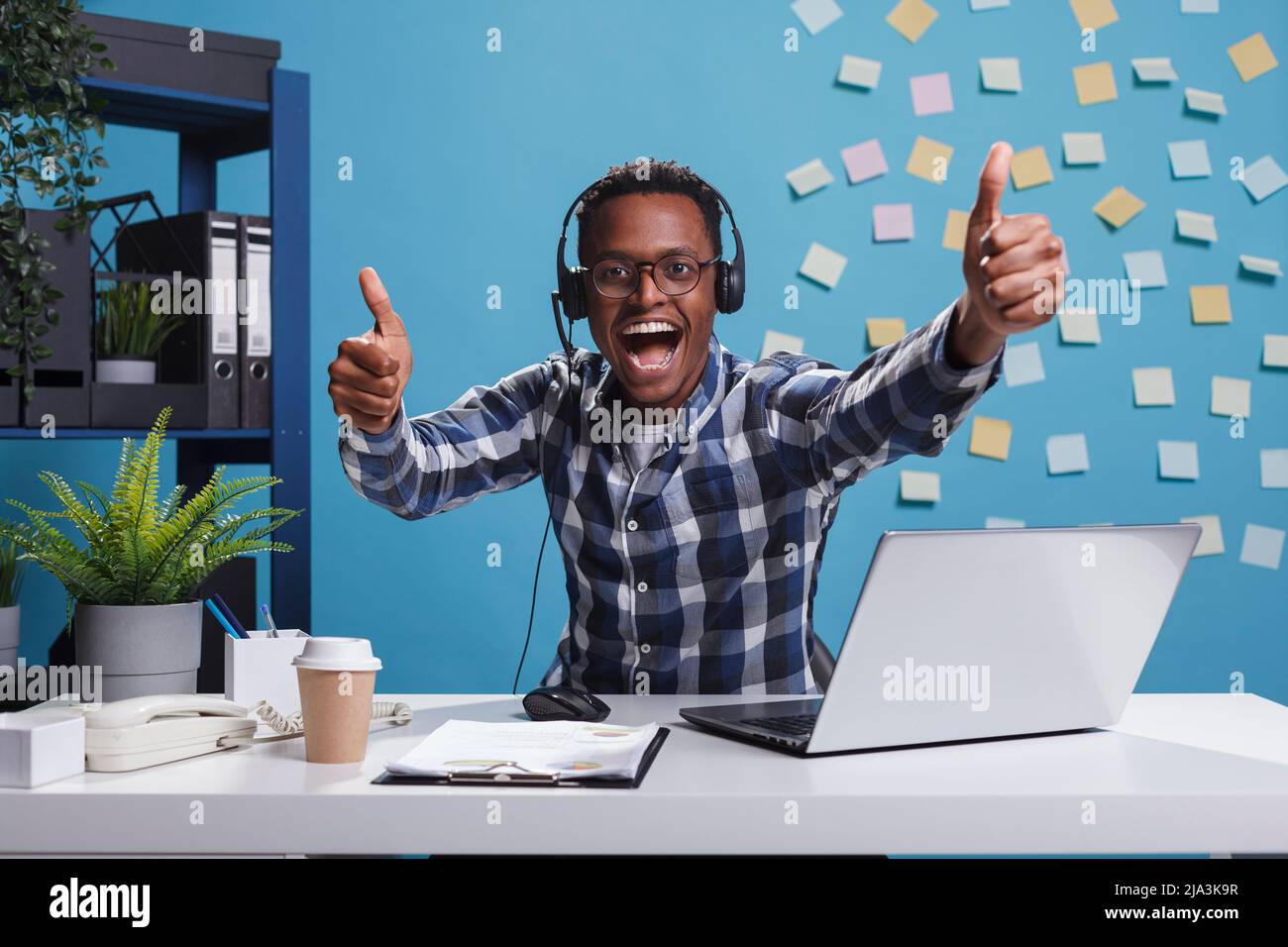 Overjoyed smiling call center operator showing thumbs up gesture with ...