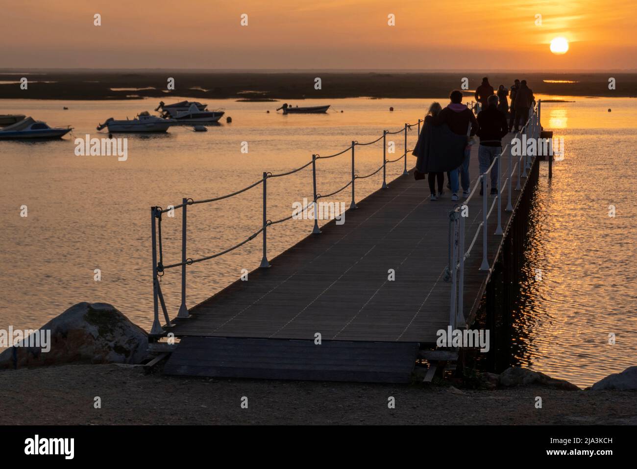 Group of people walk an wooden pathway to watch the sunset Stock Photo ...