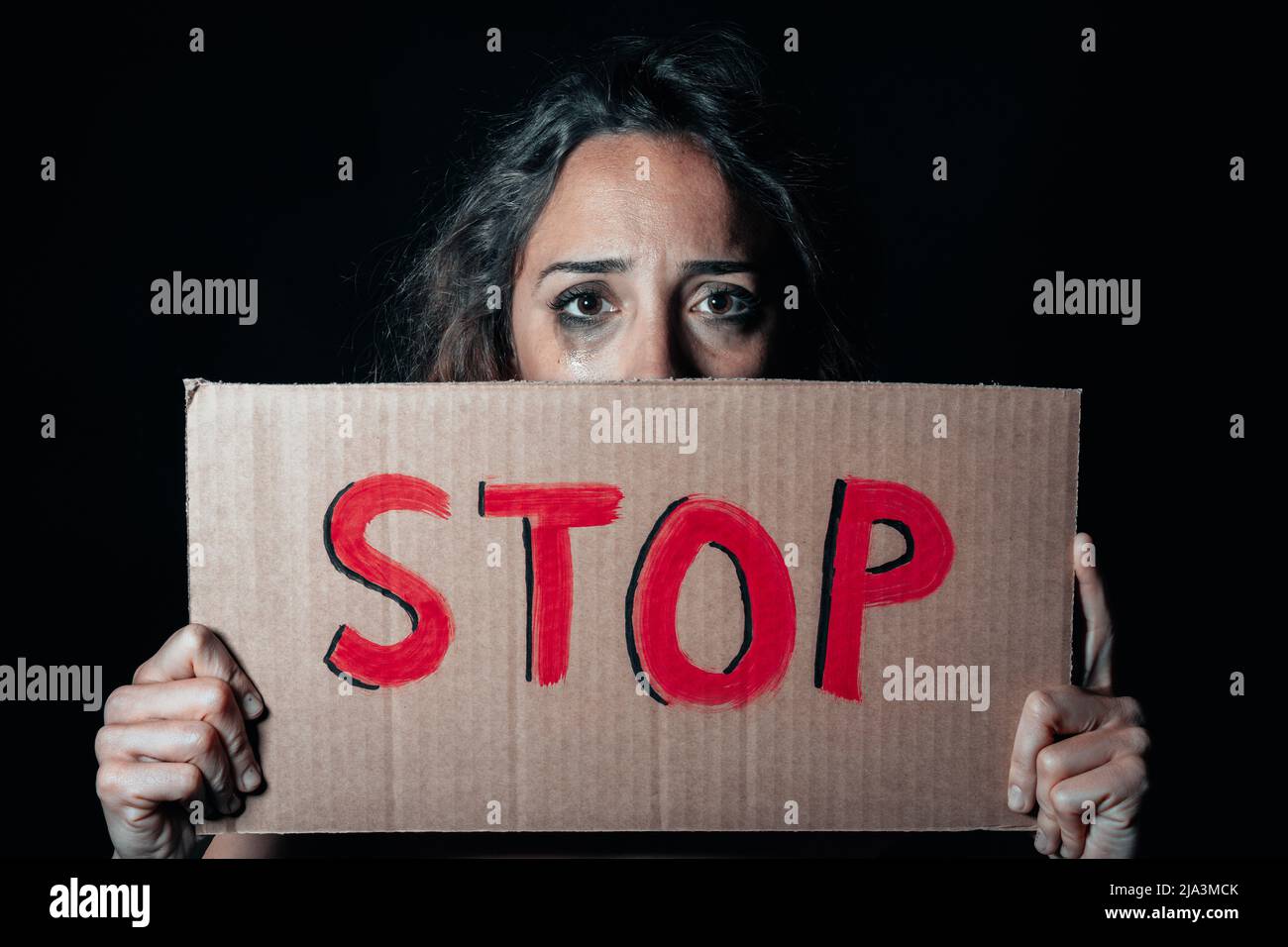 Mistreated woman victim holding a 'stop' cardboard on her hands Stock ...