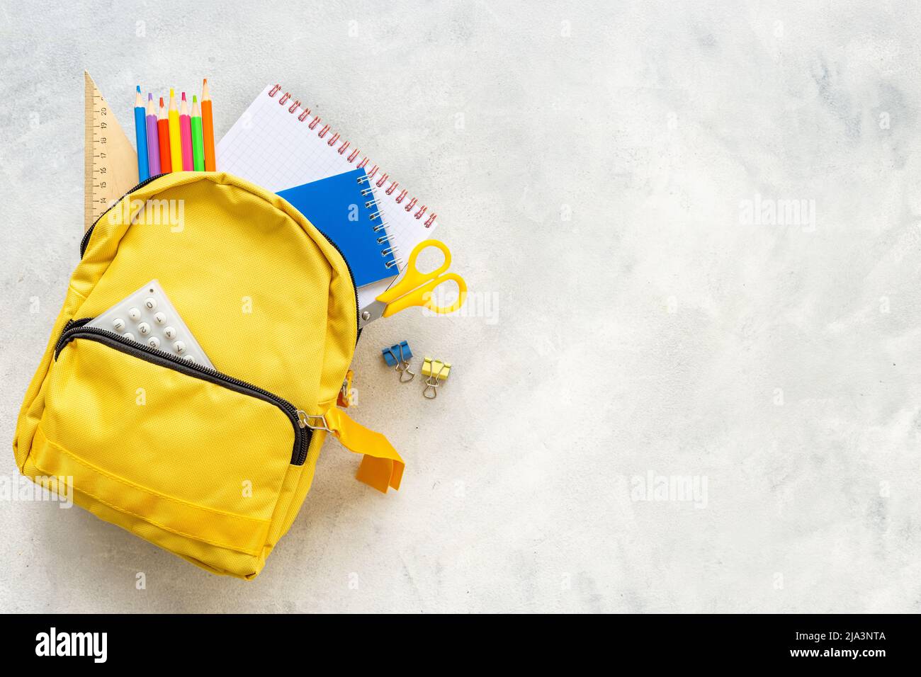 Yellow school backpack with colorful school stationery Stock Photo - Alamy