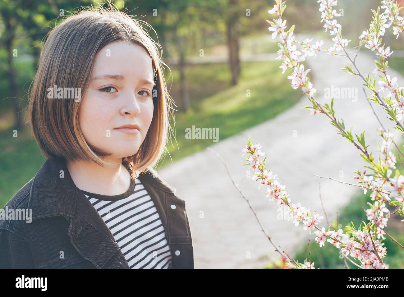Outdoor portrait of pre-teen girl posing near flowering tree. Nature ...