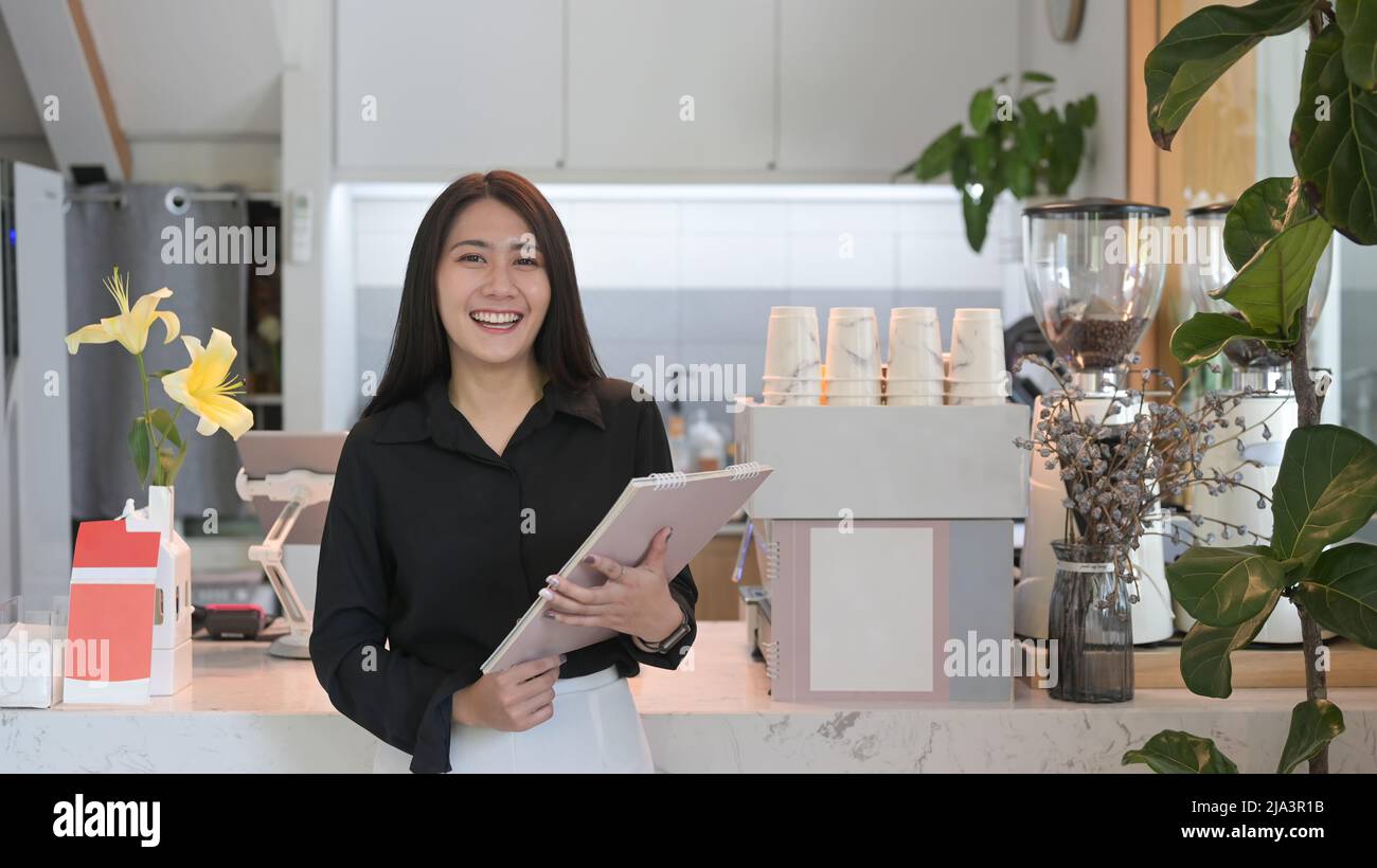 Successful female business owner standing behind counter of coffee shop ...