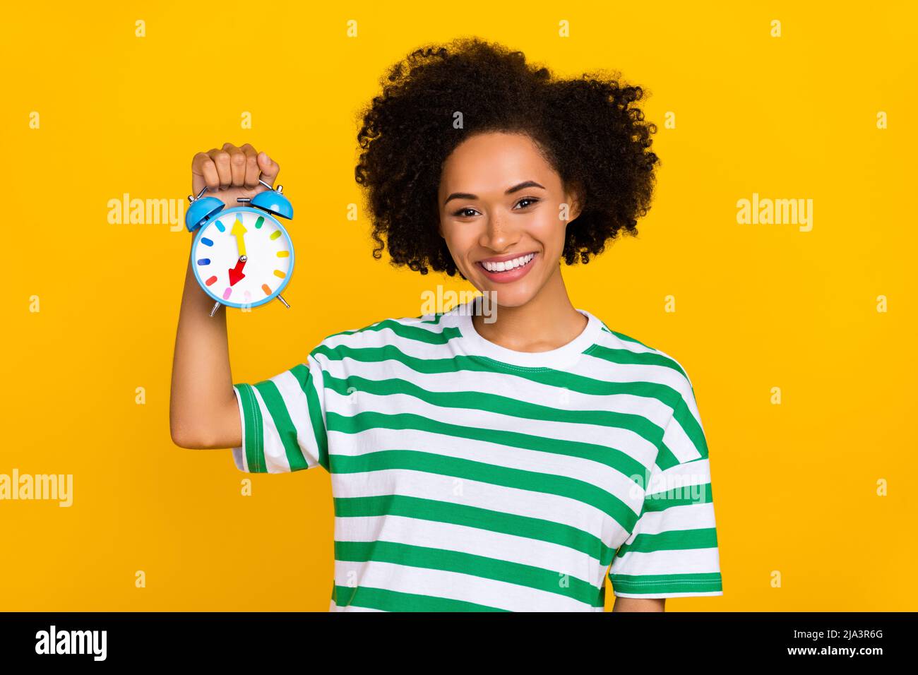 Photo of optimistic millennial lady hold clock wear striped t-shirt ...