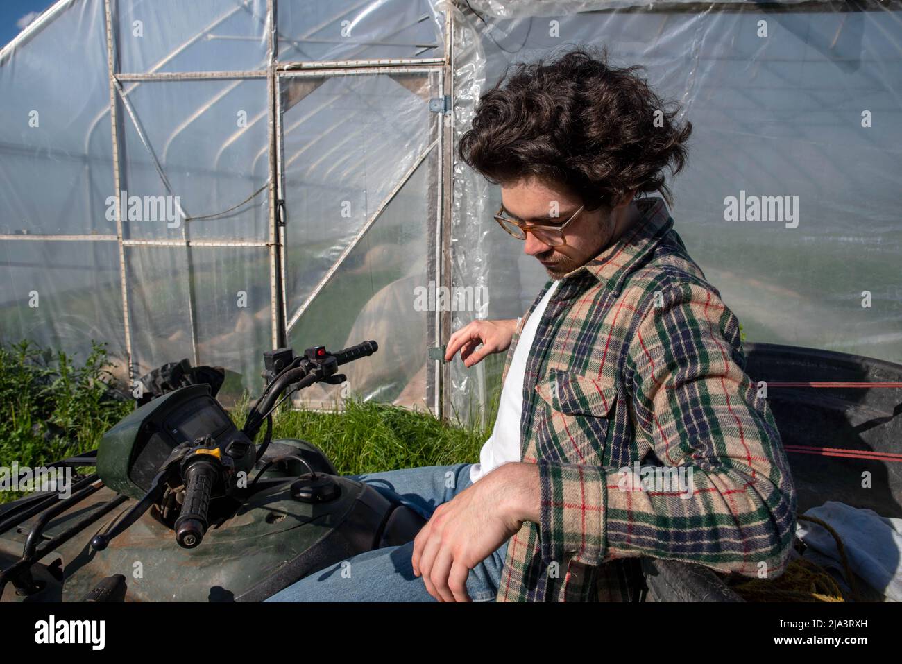 Young caucasion male farmer in a flannel shirt on an off road farm ...