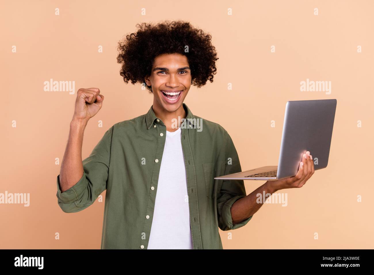 Portrait of attractive cheerful lucky wavy-haired guy using laptop ...