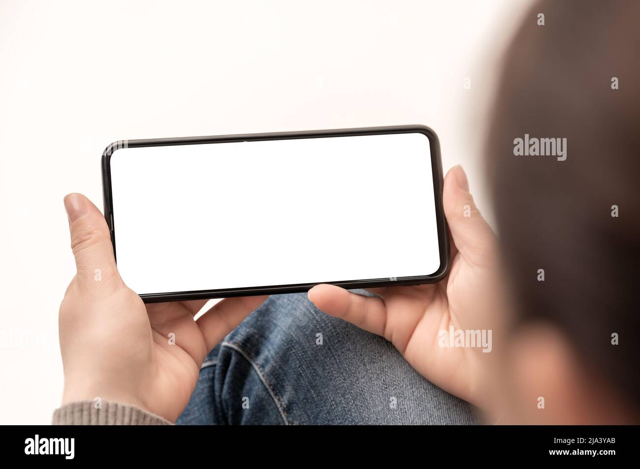 woman watching video on cell phone mockup sitting on white background. Mockup phone horizontal ...