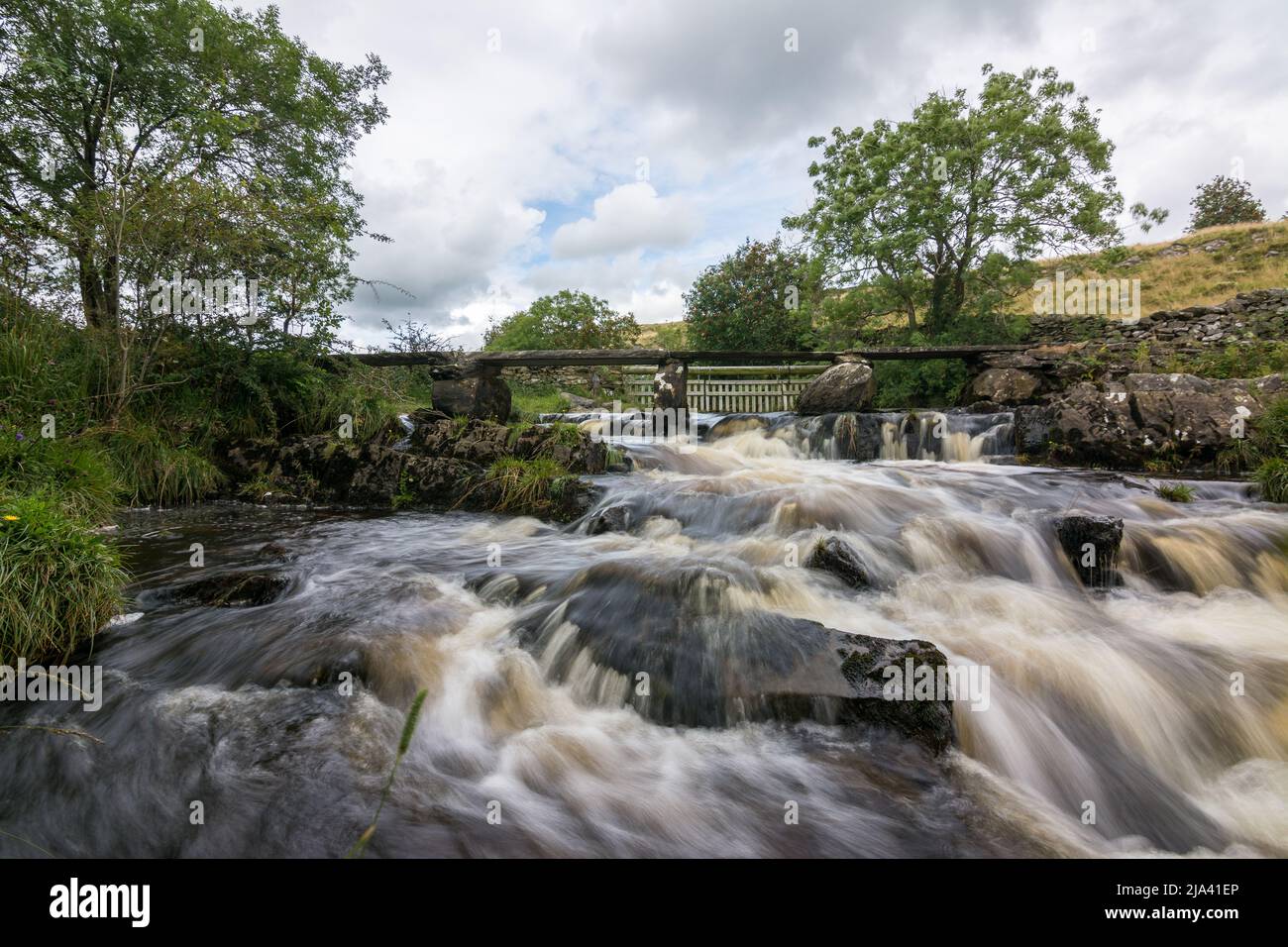 Long exposure of a fast-flowing stream rushing under a crude stone ...