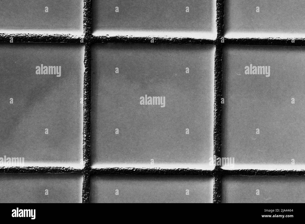 Industrial wall covered with many square grid tiles in black and white ...