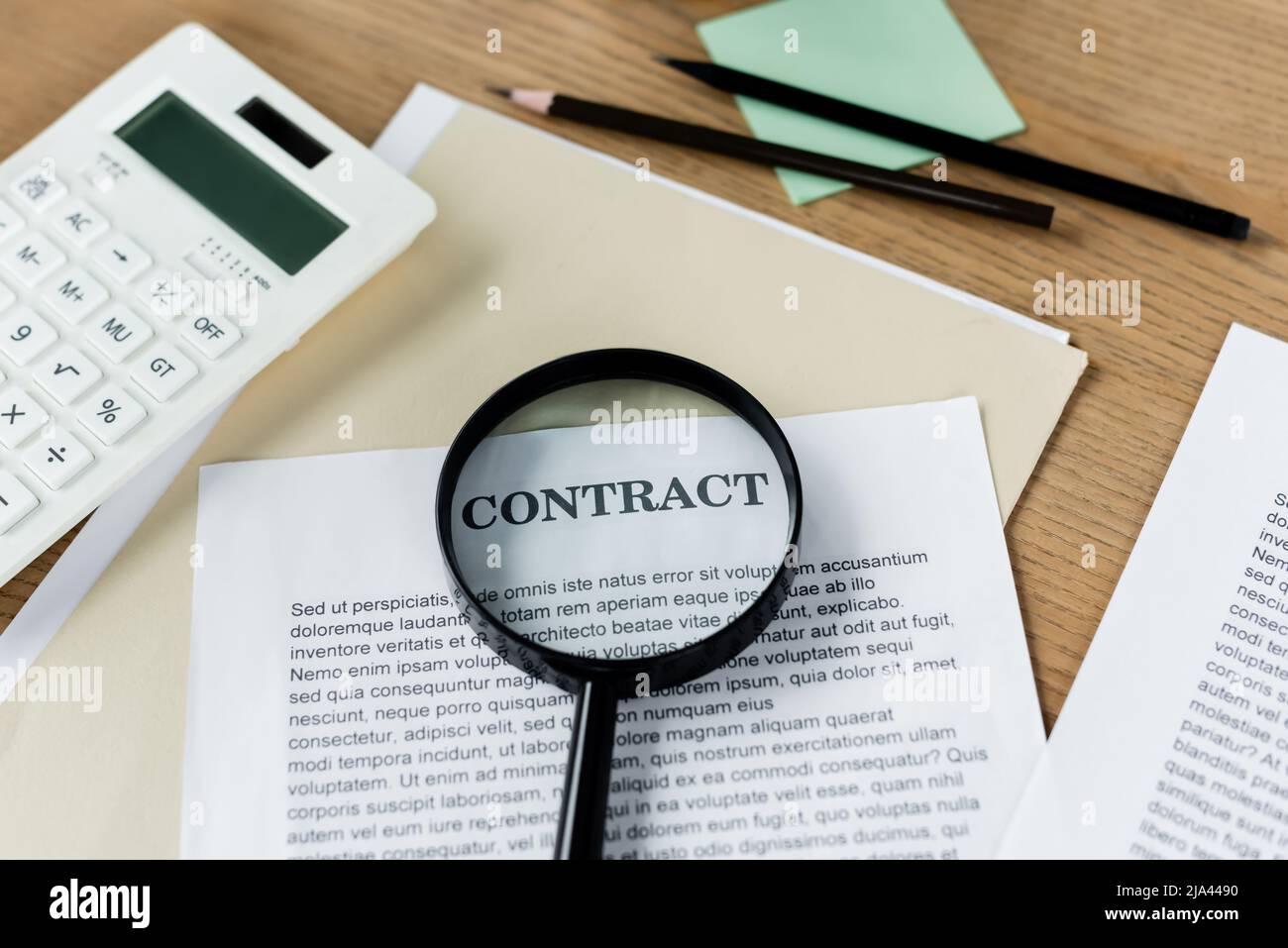 magnifier on papers with contract lettering near calculator and ...