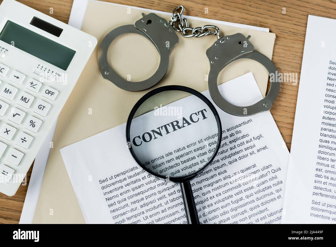 top view of magnifier on papers with contract lettering near calculator ...