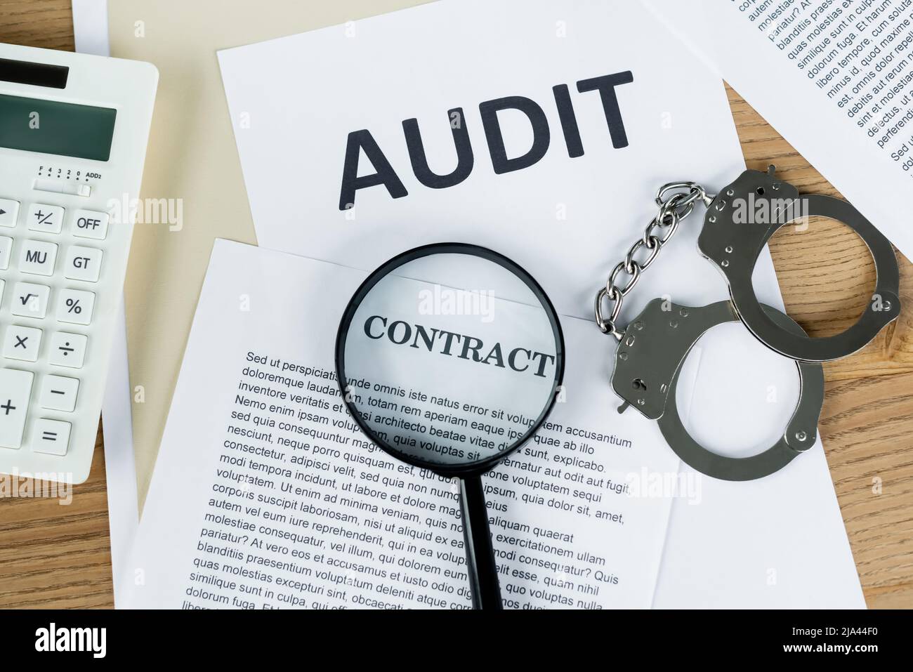 top view of magnifier on papers with audit and contract lettering near ...